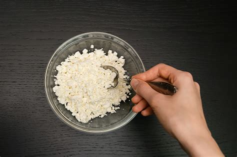 숟가락을 든 여성의 손은 검은 색 테이블에 유리 그릇에서 코티지 치즈 한 알갱이를 가져갑니다 개념에 대한 스톡 사진 및 기타 이미지 Istock
