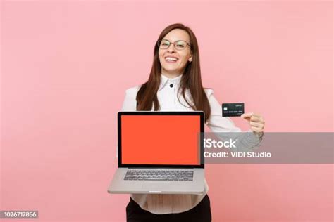 분홍색 배경에 고립 된 빈 빈 화면으로 신용 카드 노트북 Pc 컴퓨터를 들고 안경에 젊은 웃음 비즈니스 여자 여자 보스입니다 성과 경력 부입니다 광고에 대 한 공간을 복사