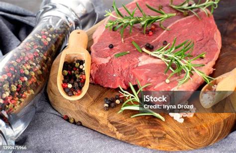 회색 앞치마에 나무 커팅 보드에 나무 숟가락 후추와 소금과 후추 밀을 곁들인 생고기 쇠고기 스테이크 0명에 대한 스톡 사진 및 기타 이미지 Istock