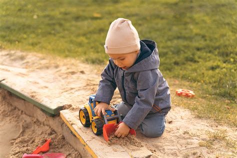 샌드 박스에서 장난감을 가지고 노는 어린이 모래 구덩이에서 놀이터에서 즐거운 어린 소년 아이들을위한 야외 창조적 인 활동 가을