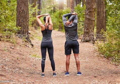 젊은 남녀 운동 선수가 뒤에서 자연에서 뛰기 전에 스트레칭하는 전체 길이 화창한 날에 소나무 숲에서 워밍업 운동을하는 두 명의 적합한 스포츠맨 스트레칭에 대한 스톡 사진 및