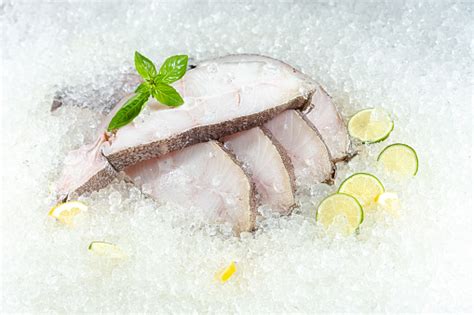 신선한 바다 바다 흰 물고기 조각으로 슬라이스 얼음에 누워 머리없는 체리 슬라이스 레몬과 라임 슬라이스 라운드 녹색 바질 빛 위에서 측면보기와 함께 주위에 누워 각얼음에