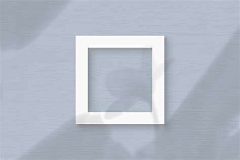 파란색회색 벽 배경에 흰색 텍스처가 있는 용지의 사각형 프레임 시트입니다 식물 그림자의 오버레이와 모형 자연 광은 이국적인 식물의 잎에서 그림자를 투사합니다 플랫 레이 0