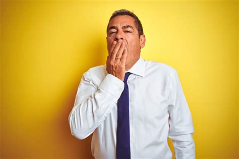 고립 된 노란색 배경 위에 서있는 잘 생긴 중년 사업가는 손으로 입을 덮는 피곤 한 하품 지루 불안과 졸음 가리기에 대한 스톡 사진 및 기타 이미지 Istock