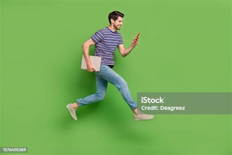 긍정적인 귀여운 남자가 줄무늬 티셔츠를 입고 높은 의사 소통 현대 가제트 격리된 녹색 배경을 입는 전체 길이 사진 남자에 대한 스톡 사진 및 기타 이미지 Istock