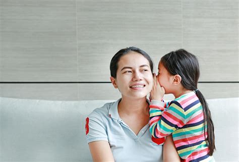 집 거실에서 엄마에게 비밀을 공유하는 행복한 아시아 어린이 소녀 엄마 귀에 뭔가를 속삭이는 꼬마 소녀 2명에 대한 스톡 사진 및 기타 이미지 Istock
