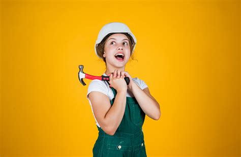 당신의 차를 검사합니다 아이는 건설 현장에서 헬멧을 착용합니다 건물 도구 망치를 가진 십 대 소녀 빌더 수리 작업에 아이