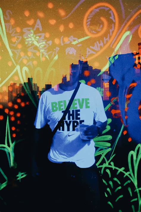 흰색과 검은 색 크루 넥 티셔츠를 입은 남자가 낙서와 함께 벽 근처에 서 있습니다 사진 Unsplash의 무료 의복 이미지