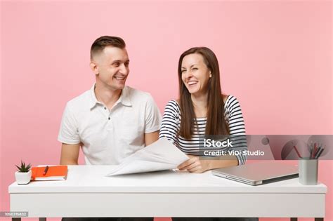 비즈니스 여자 남자 동료 들을 웃 고 두 영 현대 노트북 파스텔 핑크 배경에 고립 된 흰색 책상에서 작업 앉아 성과 경력 개념입니다 광고 청소년 공동 작업 공간을 복사