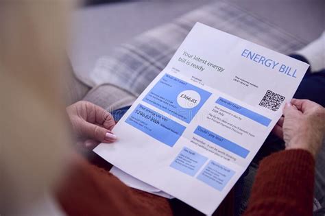 Close Up Of Senior Woman At Home Looking At Energy Bill During Cost Of