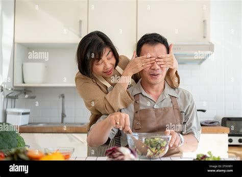 A Happy Playful Asian Wife Is Teasing Her Husband While He Is Cooking