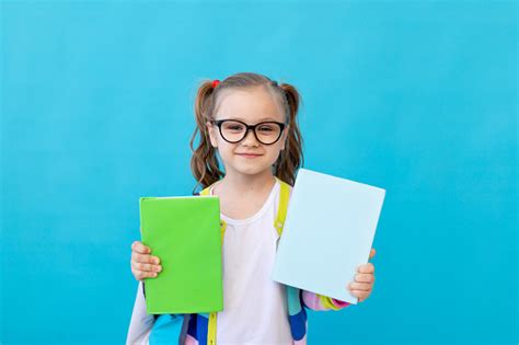 두 개의 빈 책이있는 줄무늬 재킷에 안경을 쓴 귀여운 어린 소녀의 초상화 교육의 개념 사진 스튜디오 파란색 배경 텍스트 장소 6 7 살에 대한 스톡 사진 및 기타 이미지