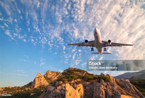 큰 흰색 비행기는 일출 바위 위에 날고 있다 여객기 산 구름과 화려한 푸른 하늘 풍경입니다 여객기 착륙 비즈니스 여행입니다 상업 비행기입니다 비행기에 대한 스톡 사진 및