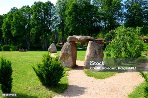 흙 길 옆 의 공공 공원 한가운데에 있는 세 개의 바위 또는 바위로 만든 구조와 폴란드의 물체 뒤에 울창한 숲이나 황무지가있는 관목과 같은 작은 스톤 헨지 폴란드에 대한