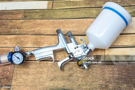 나무 바닥에 페인트 스프레이 산업 회화 및 코팅에 사용되는 산업 크기 스프레이 건을 들고 화가의 팔 손의 이미지 배경 클리핑