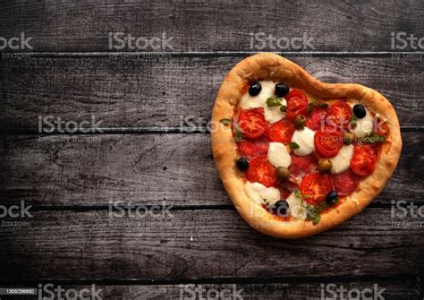 페퍼로니 체리 토마토 마늘 모짜렐라 치즈 올리브 오일을 나무 테이블에 얹은 하트 모양의 이탈리아 피자 발렌타인 데이에 대한 사랑의 개념 맨 위 보기입니다 공간을 복사합니다