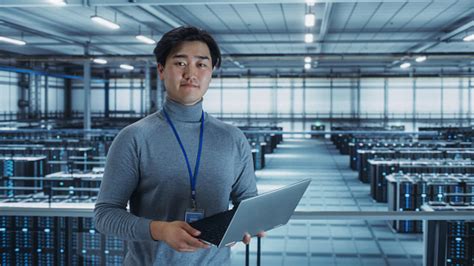 랩톱 컴퓨터를 사용하는 데이터 센터 엔지니어의 초상화입니다 사이버 보안을 위한 데이터 보호 네트워크와 함께 작업하는 한국 남성 시스템 관리자와 서버룸 전문가 시설 인물