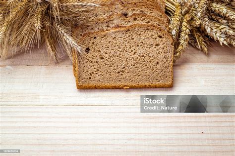 빵을 자른다 나무 질감 배경에 밀 곡물 귀 또는 스파이크 식물 소박한 전통 빵의 신선한 덩어리 거친 빵과 부스러기가있는 호밀 빵집 바이오 성분 매우 건강한 씨앗 0명에 대한
