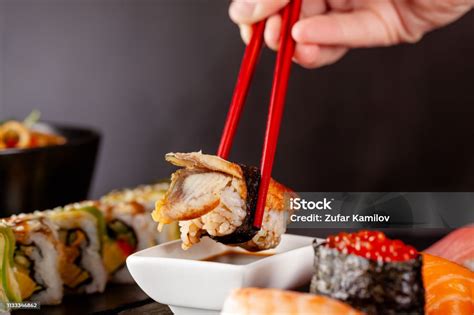 일본 요리의 컨셉 한 소녀는 붉은 중국 젓가락을 들고 레스토랑에서 초밥을 먹는다 배경 이미지입니다 인기 일본 음식 복사 공간 가지 식물 부위에 대한 스톡 사진 및 기타