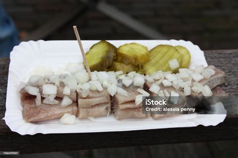 전형적인 네덜란드 요리 길거리에서 음식을 먹기 위한 흰색 마분지 쟁반 오이와 작은 조각의 생 흰 양파와 함께 제공 되는 자연 치료를 받지 않은 신선한 청 어 청어에 대한