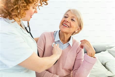 건강 방문자 및 가정 방문 중 노인 여성 노인 환자를 검사하는 젊은 여성 의사 흰 코트를 입은 젊은 여성 의사가 선배 여성을 검사하고 있다 사진 Unsplash의