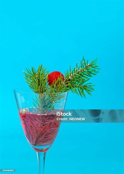 신선한 녹색 소나무 가지로 장식 된 작은 거품이있는 이국적인 분홍색 칵테일 음료가있는 현대적인 유리 청록색 배경에 눈송이와 은공이있는 붉은 장식 크리스마스 공 0명에 대한