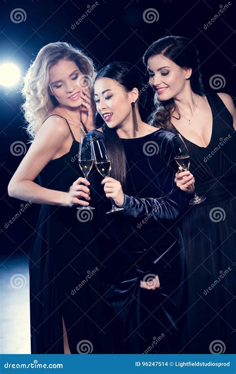 Young Women In Stylish Dresses Partying And Drinking Champagne Together