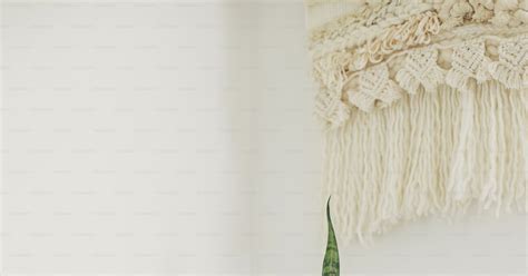 뱀 식물을 배경으로 한 나무 침대 옆 탁자에 있는 세련된 소금 램프와 흰색 스칸디나비아 방의 보호 장식 보호 침실에서 차분하고