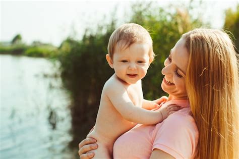 Free Photo Cheerful Mother Holds Naked Baby In Her Arms