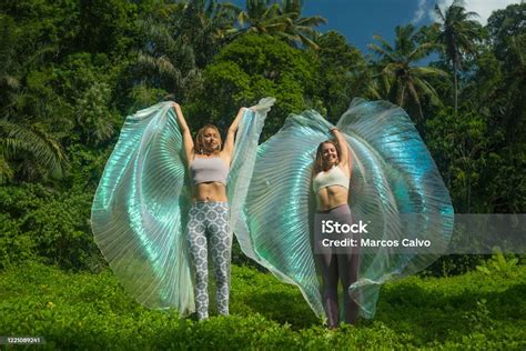 피트 니스와 건강 한 라이프 스타일 개념에서 자유와 자연을 즐기는 열 대 숲에서 날개와 함께 아크로 요가 운동 성능을 함께 하 고 젊은 아름 답 고 행복 한 여자 요가에