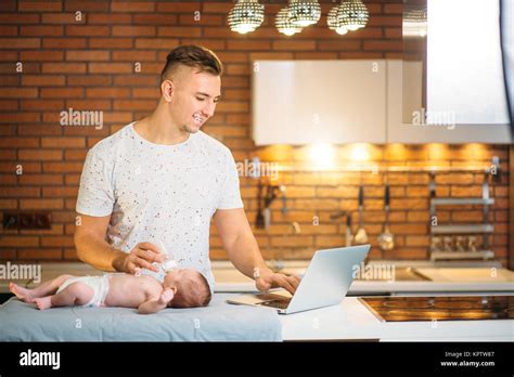 Dad Trying To Work While Standing With His Newborn Babe In Home Office Interior Stock Photo Alamy