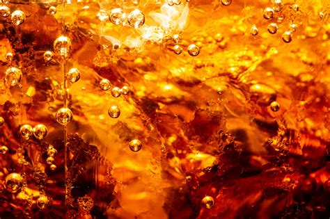 매크로 콜라 음료 배경 어두운 콜라 배경에서 얼음 조각의 보기를 닫습니다 유리 벽에 거품과 매크로 거품이 있는 달콤한 여름 차가운 음료의 표면 표면 상단으로 피징 또는