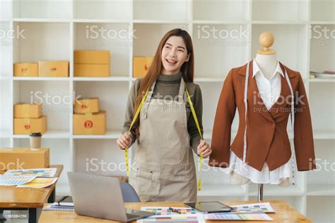 여성 패션 디자이너는 아늑한 워크샵 스튜디오 드레스 메이커 세련된 수제 옷과 의류 랙 근처에 서 있는 바느질 여성에서 고객을위한