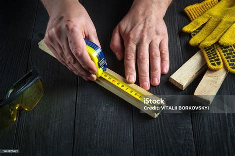 목수 또는 목공인은 건설 테이프를 사용하여 나무 조각의 길이를 측정합니다 직장에서 주인의 손 클로즈업 목공 작업장의 작업 환경 개선에 대한 스톡 사진 및 기타 이미지