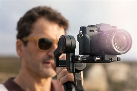 3 축 야외 Vlogger 짐벌 녹화 콘텐츠 디지털 카메라 안정제 짐벌 보관 비디오를위한 여행을 문서화하는 카메라를 손에 든 남자 짐벌을 손에 들고 비디오 그래퍼 개념