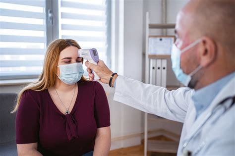 숙련 된 의사가 의사 사무실에서 적외선 온도계로 여성 환자의 체온을 검사합니다 20 24세에 대한 스톡 사진 및 기타 이미지 20 24세 2명 55 59세 Istock