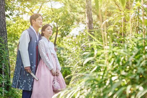 한복을 입고 숲길 또는 공원을 걷고 있는 아름답고 멋진 젊은 아시아 한국 남녀 모델 Фотографія Stock Adobe Stock