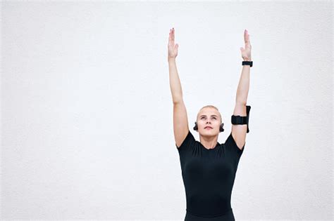 헤드폰으로 음악을 듣고 흰색 벽 배경에 스트레칭 검은 스포츠웨어를 입고 꽤 맞는 소녀 공간을 복사합니다 개념에 대한 스톡 사진 및 기타 이미지 Istock