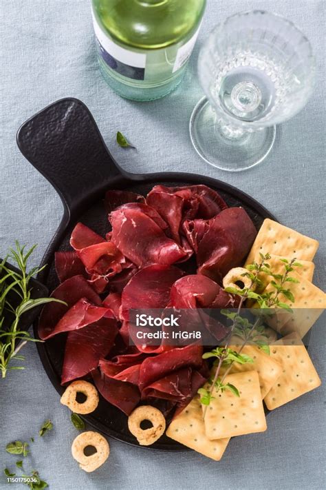 이탈리아 브 레 아 올라는 파란 리넨 축제 식탁보에 향기로운 허브가 있는 화이트 와인 크래커 그리 시 니와 타 갈리와 함께 테이블에 있는 쟁반에 슬라이스 했다 고기에 대한