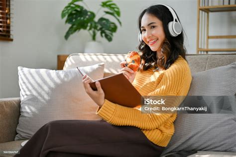 책을 읽고 맛있는 빵을 즐기면서 음악을 듣는 아시아 여성 20 24세에 대한 스톡 사진 및 기타 이미지 20 24세 거실