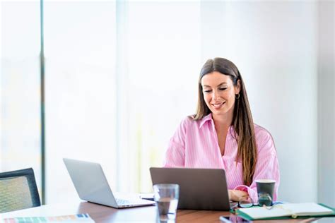책상에 앉아 현대적인 사무실에서 일하는 동안 노트북을 사용하는 웃는 여성 사업가 30 34세에 대한 스톡 사진 및 기타 이미지 30 34세 거래자 금융 Istock