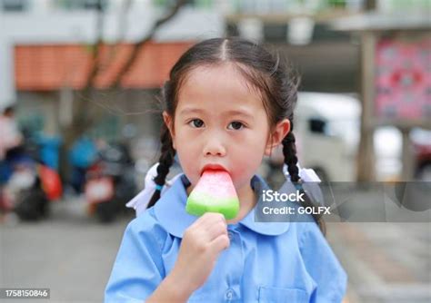 아이스크림을 먹고 있는 교복을 입은 어린 아시아 어린이 소녀의 초상화 2 3 살에 대한 스톡 사진 및 기타 이미지 2 3 살