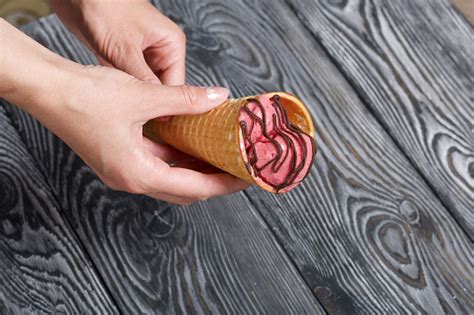 여자는 딸기 아이스크림을 손에 들고 와플 콘에 담겨 있다 초콜릿으로 장식 흑백으로 칠해진 소나무 판의 배경에 대해 냉동된에 대한 스톡 사진 및 기타 이미지 Istock