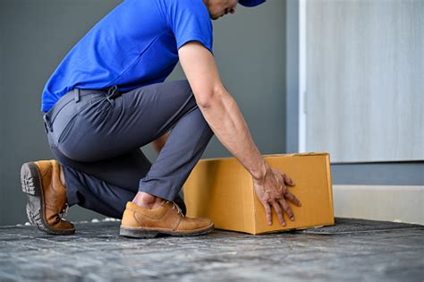 파란색 유니폼을 입은 배달원이 고객의 집 앞에 소포를 배치하는 모습을 클로즈업합니다 30 34세에 대한 스톡 사진 및 기타 이미지 30 34세 고객 나무 상자
