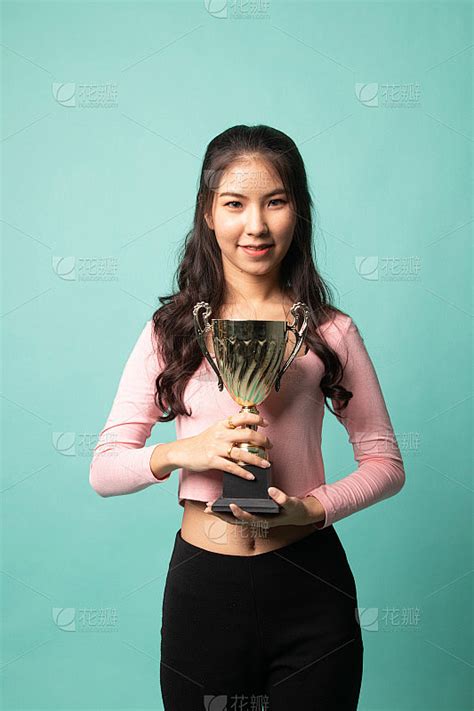 成功的年轻亚洲女性拿着奖杯。