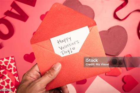 분홍색 배경에 빨간색과 분홍색 하트 모양의 선물 상자 봉투 종이 하트 리본 리본 열린 봉투에 손으로 쓴 사랑의 메모가 있는 평평하게 놓인 발렌타인 데이 구성 0명에 대한