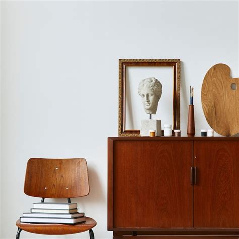 디자인 복고풍 티크 옷장 포스터 프레임 이젤 책 장식 및 그림 액세서리가 있는 예술가 작업 공간의 세련된 구성 템플릿 프리미엄 사진