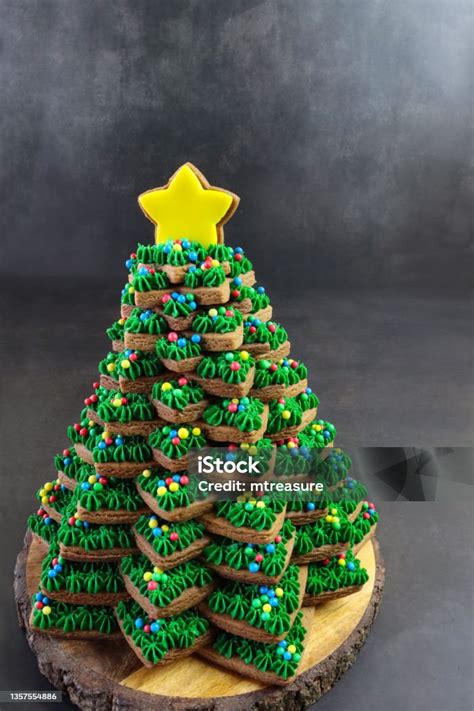 노란 아이스 스타 비스킷 나무 케이크 스탠드 검은 배경 전경에 초점을 얹은 여러 가지 색상의 사탕 공으로 장식 된 녹색 버터 장식 소용돌이로 파이프 쌓인 진저 브레드 스타