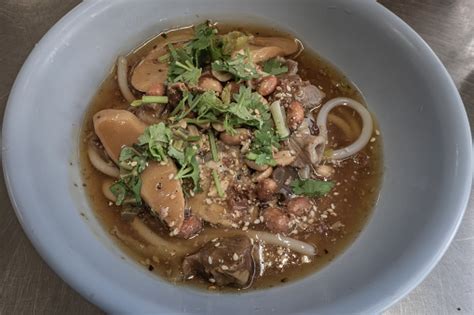 하이난 마른 쌀 국수는 스테인레스 스틸 테이블에 태국 스타일의 찐 돼지 고기와 함께 있습니다 많은 종류의 재료로 매우 맛있는 현지 음식 정상에서 비스듬한 전망 거리에 대한