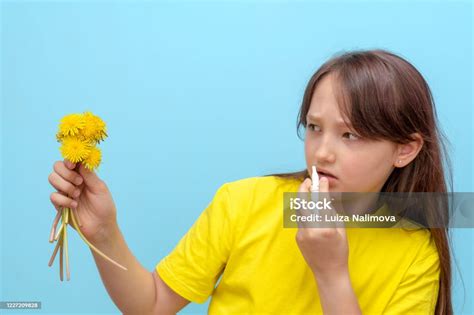 파란 배경에 꽃과 항 알레르기 스프레이를 손에 들고 있는 어린이 소녀의 초상화 꽃에 계절 꽃가루 알레르기의 개념 12 13세에